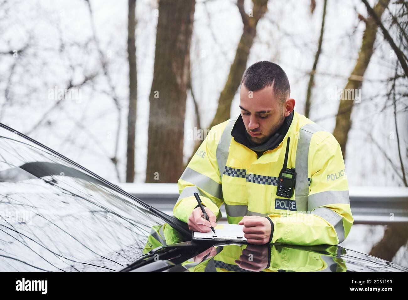 Male police officer in green uniform checking vehicle on the road Stock ...