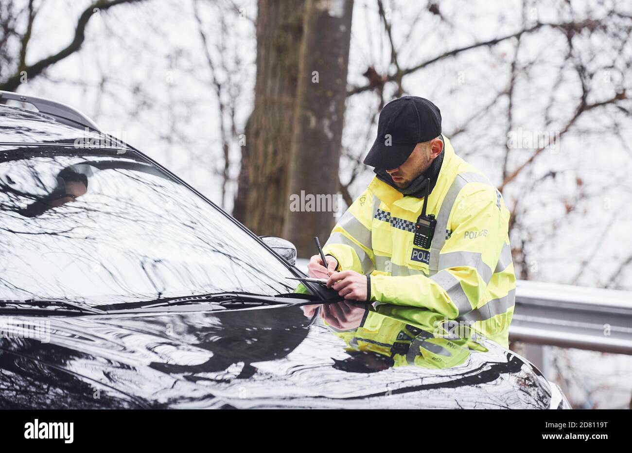 Male police officer in green uniform checking vehicle on the road Stock ...