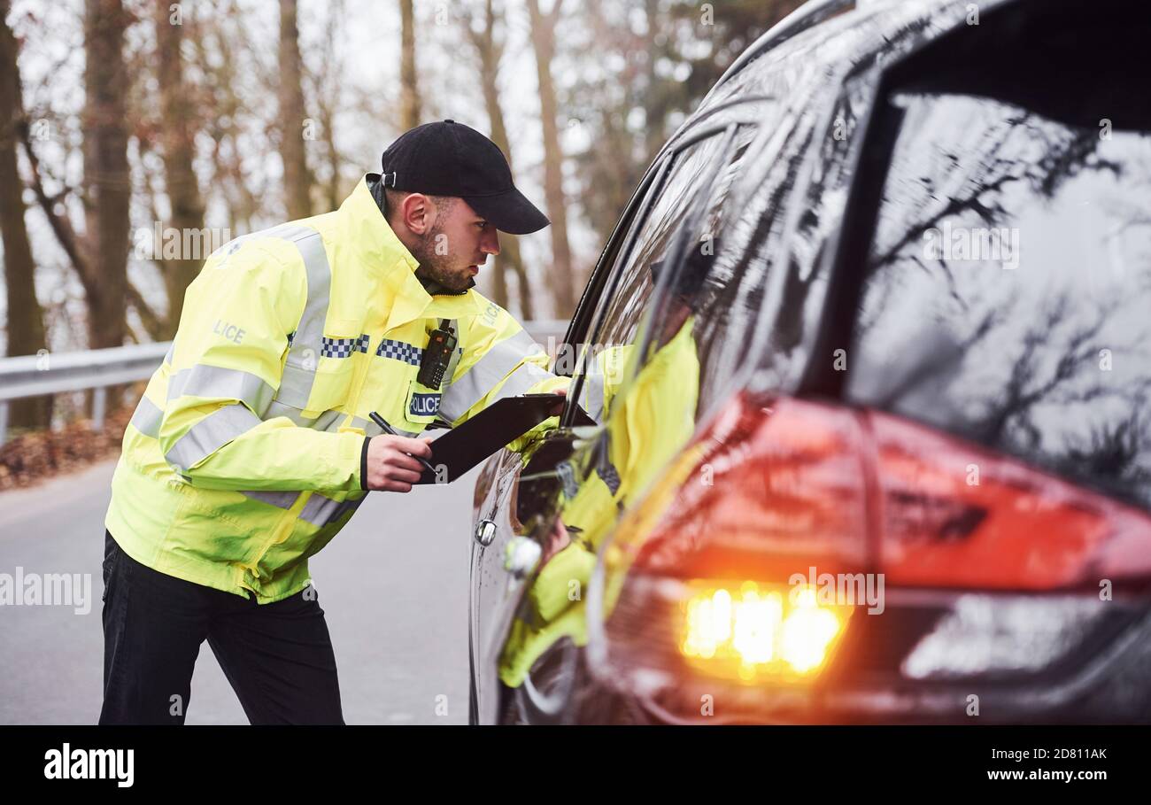 Male police officer in green uniform checking vehicle on the road Stock ...