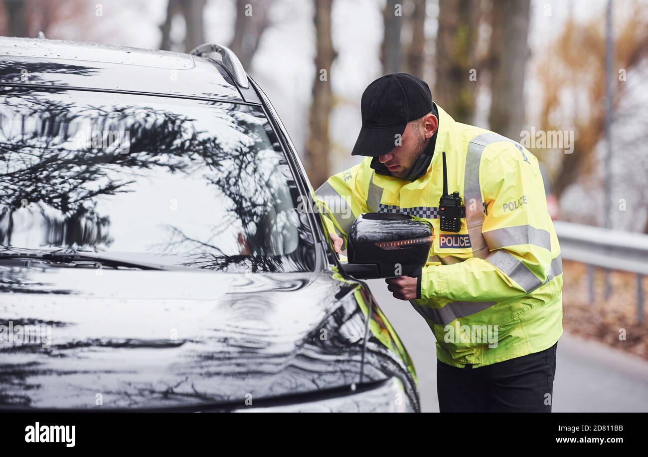 Male police officer in green uniform checking vehicle on the road Stock ...
