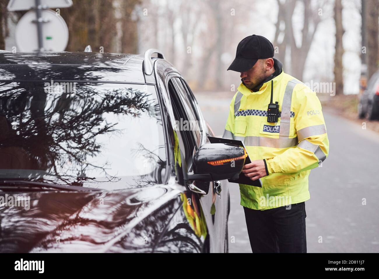 Male police officer in green uniform checking vehicle on the road Stock ...