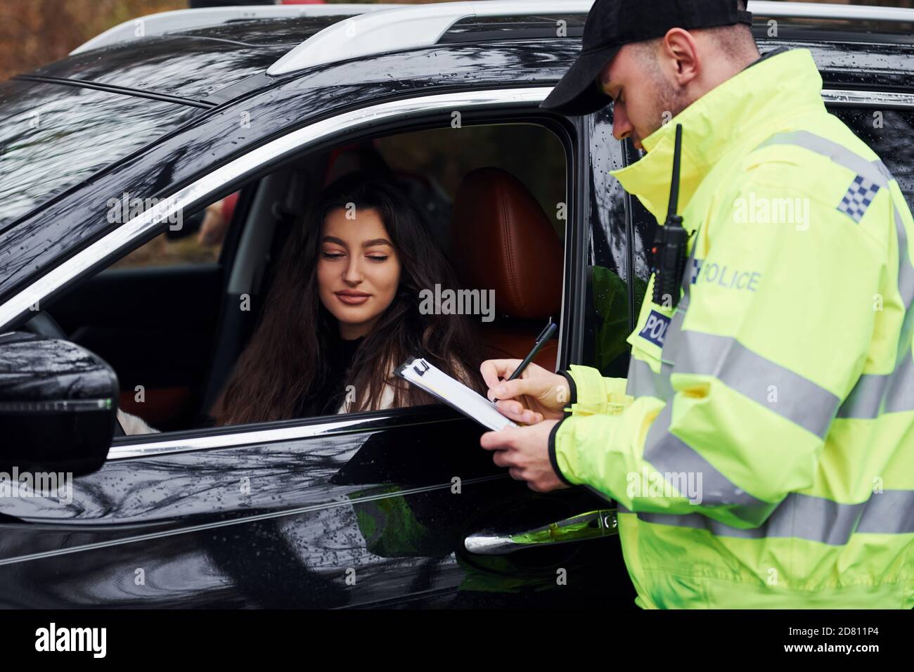 Male police officer in green uniform with notepad checking vehicle on ...