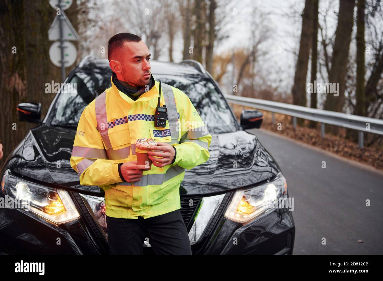 Male police officer in green uniform taking a break with donut on the ...