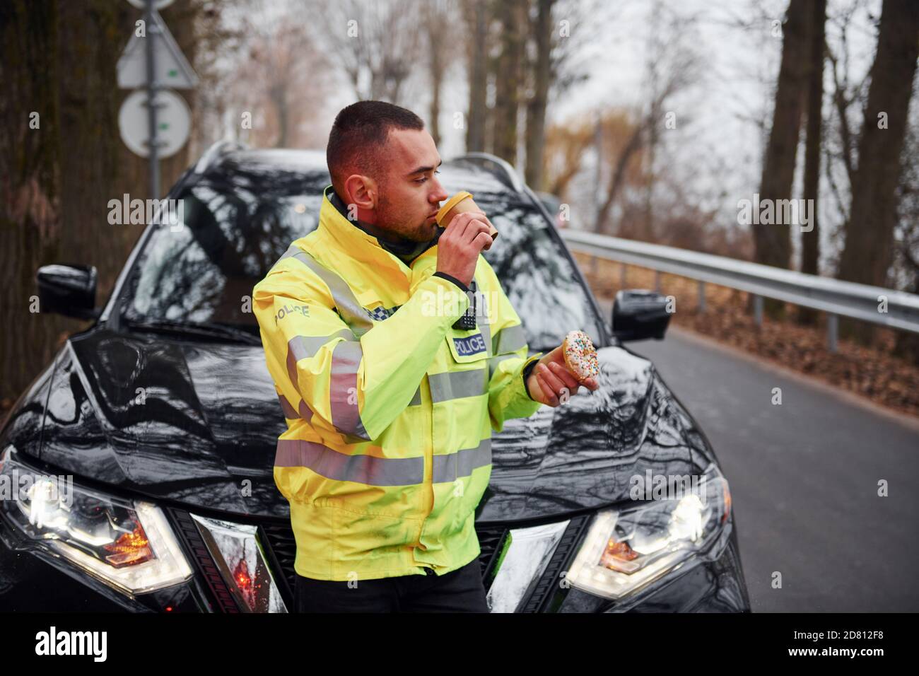 Male police officer in green uniform taking a break with donut on the ...