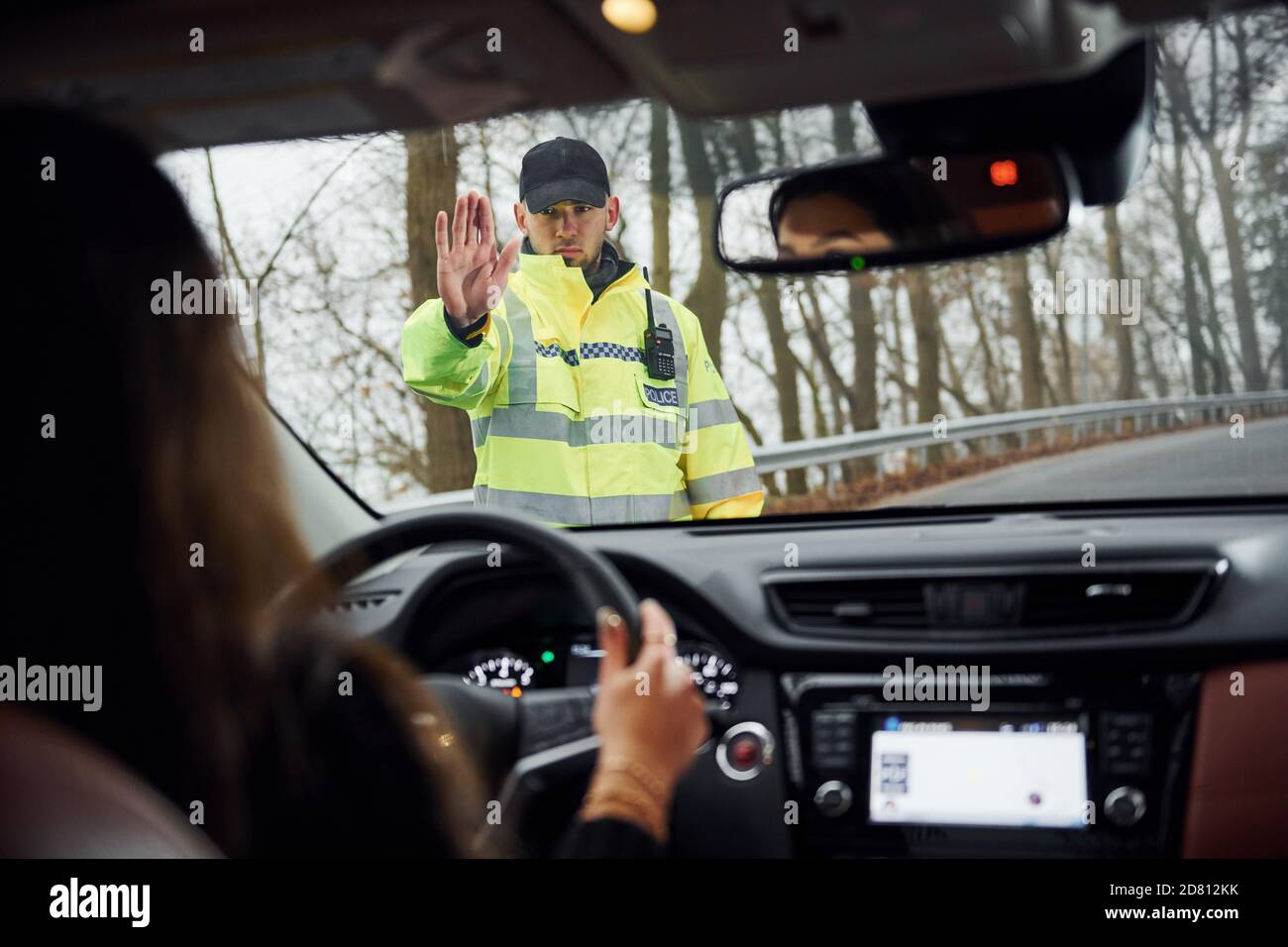 Male police officer in green uniform stops vehicle with female driver ...