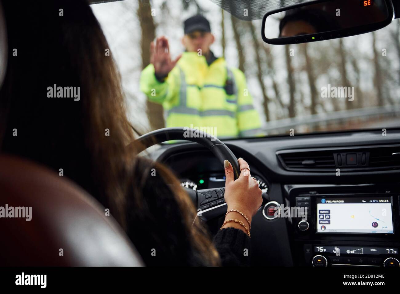 Male police officer in green uniform stops vehicle with female driver ...