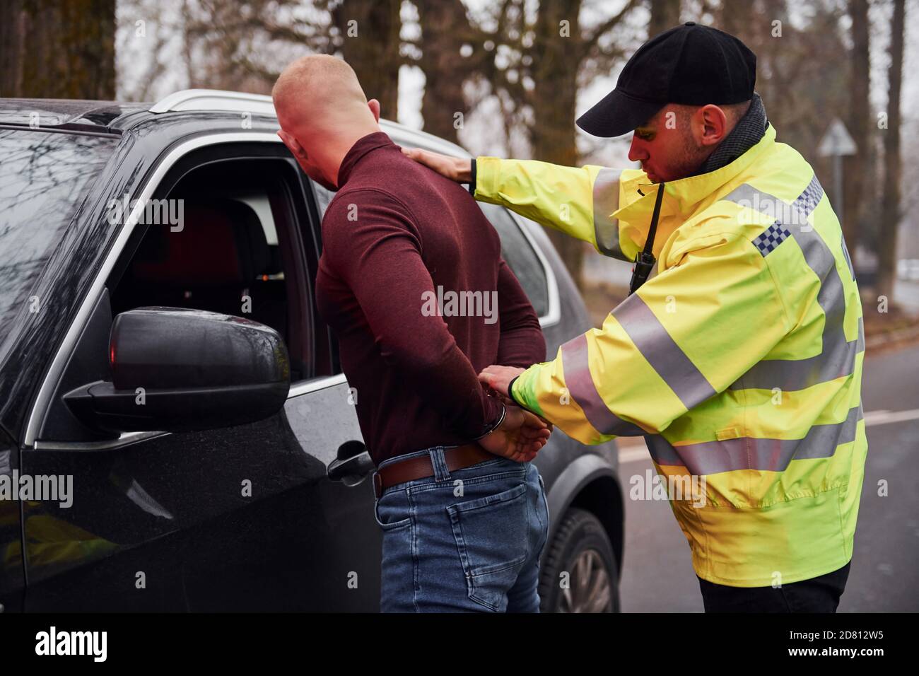 The police officer in green uniform detains the offender near car ...