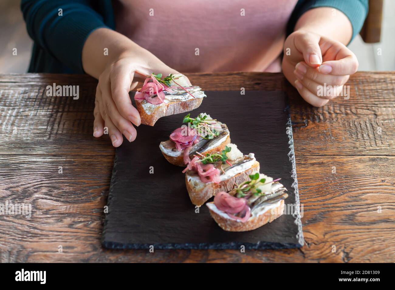 Young woman eating delicious open sandwiches with smoked fish, cream ...