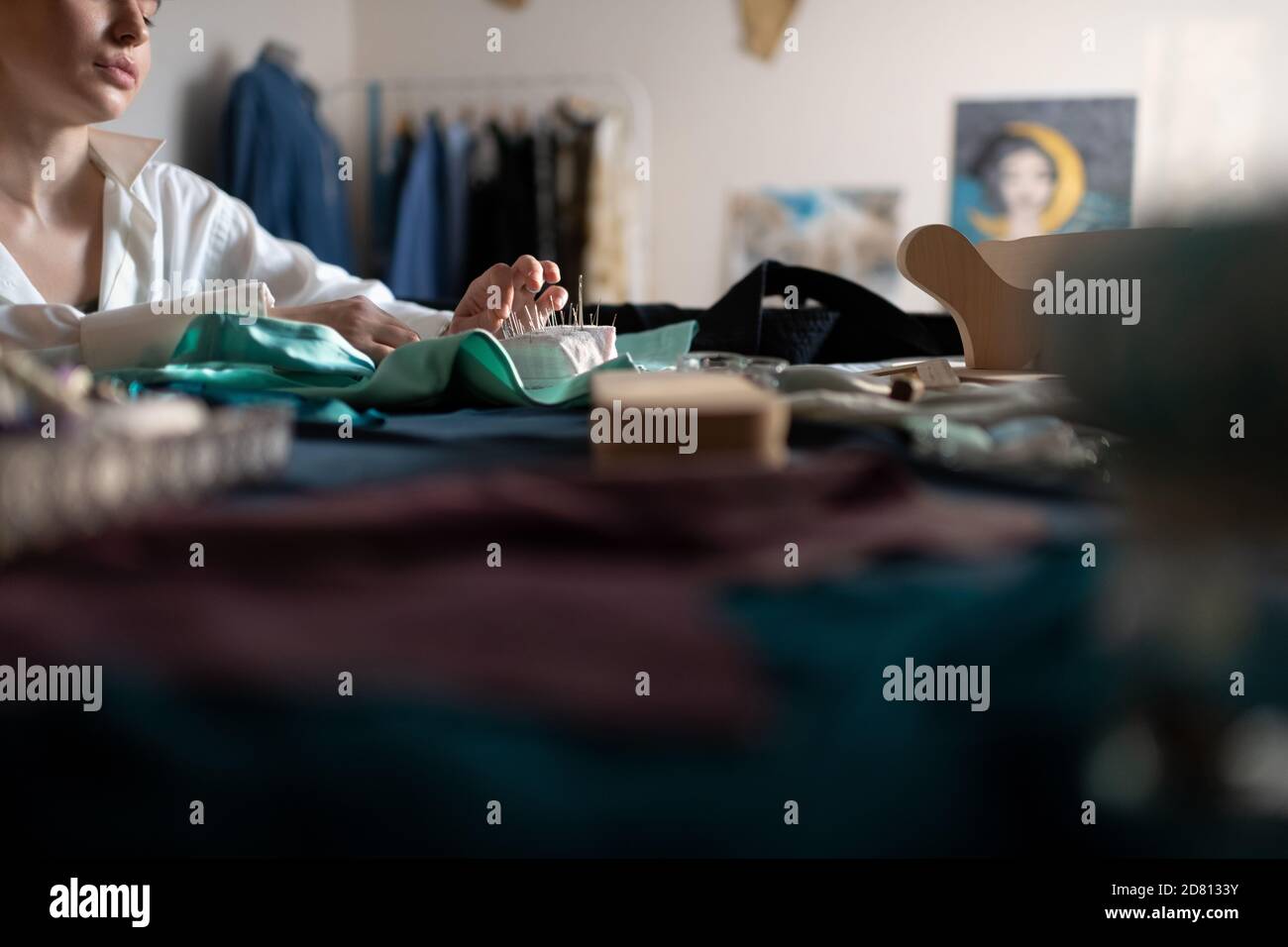 Low angle of cropped seamstress picking needle while sewing pieces of ...