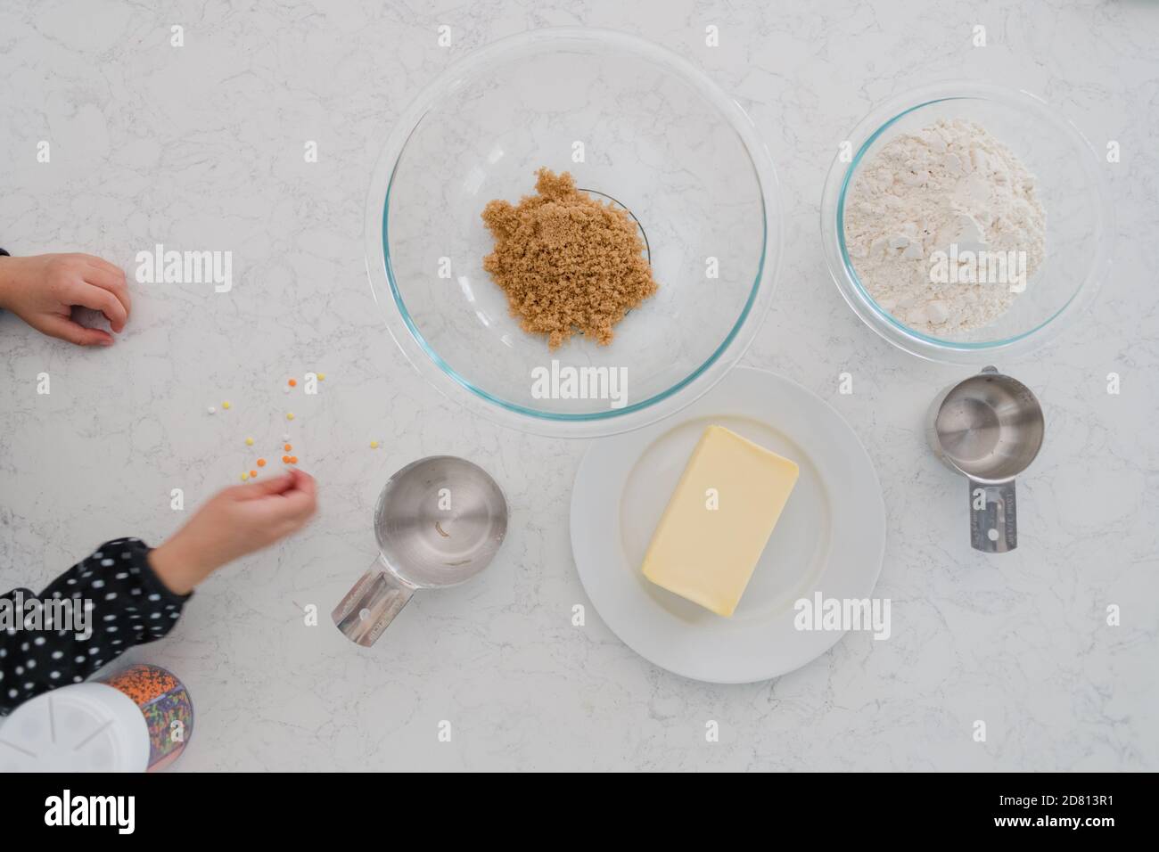 baking ingredients on counter with child eating sprinkles Stock Photo ...