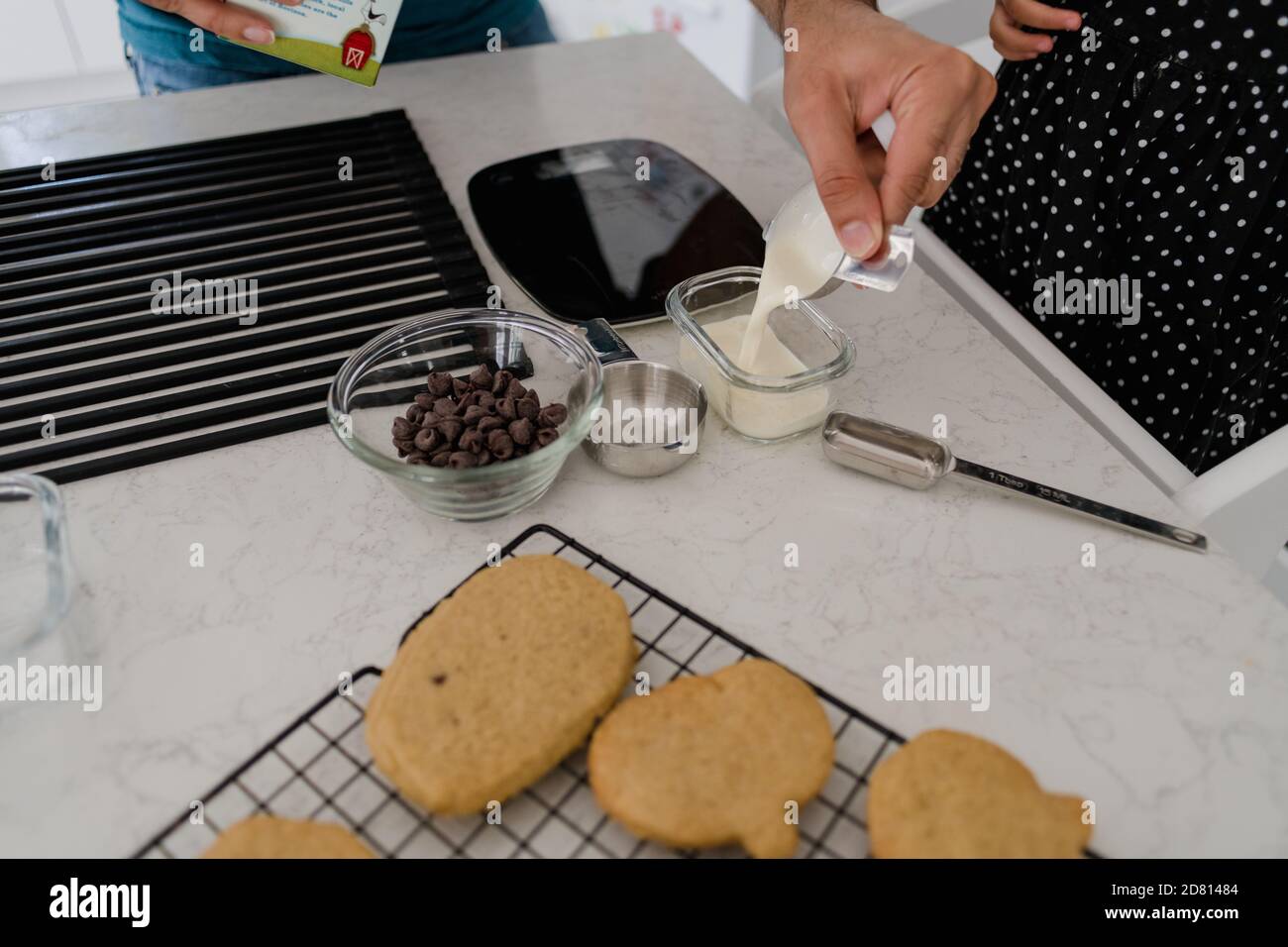 close up shot of father pouring milk for cookie baking ingredients ...