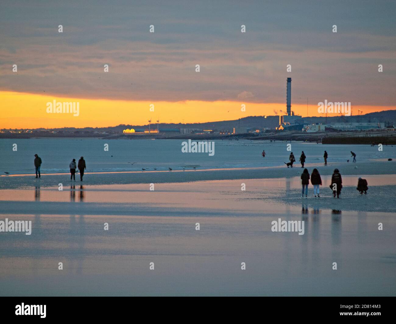 People wander on the beach at low tide as the sun goes down ifiguresn ...