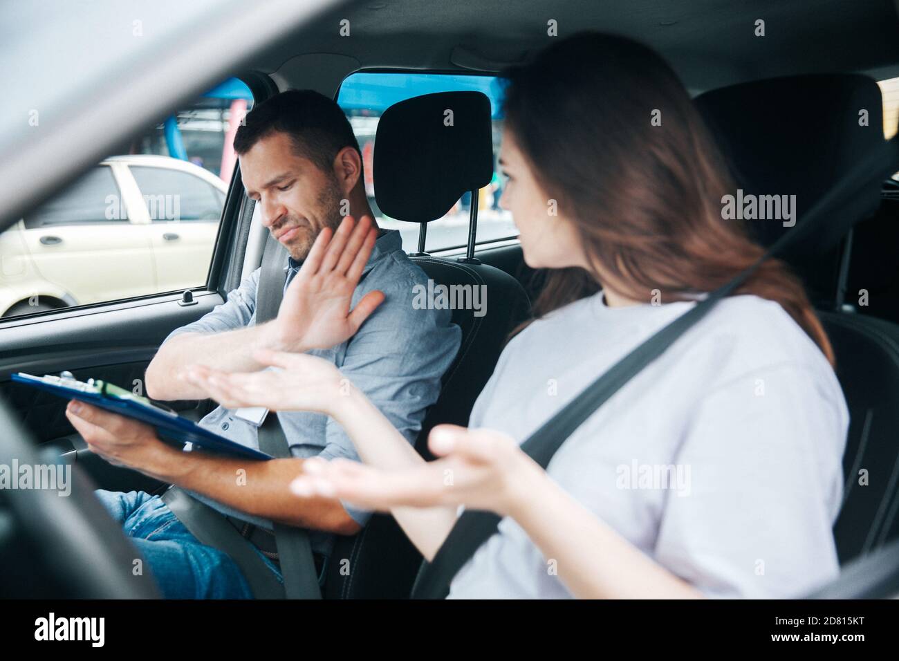 Young worried woman in white shirt and angry male driving instructor ...