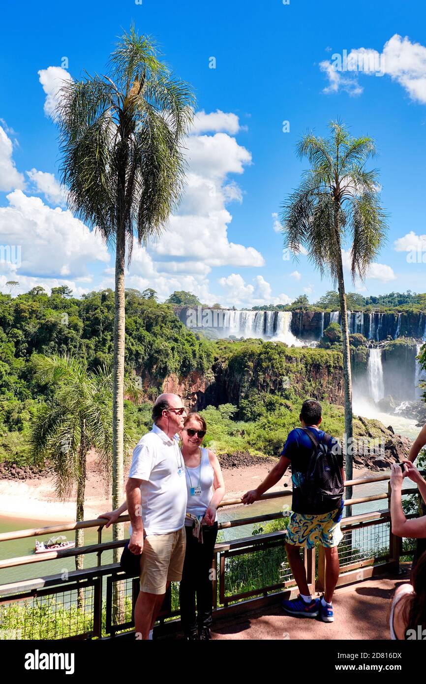 Tourists taking pictures of themselves with palm trees and Iguazu Falls ...
