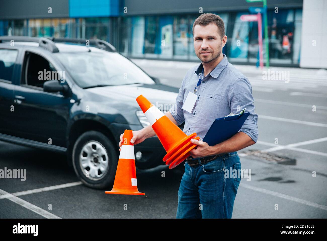 Driving instructor loves his job. Young attractive man standing with ...