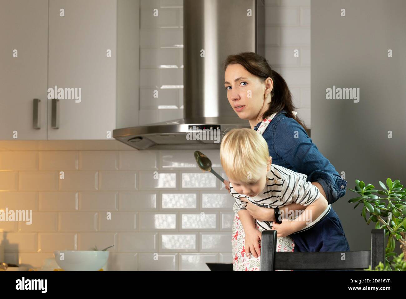 Beautiful mother watching child while preparing dinner. Happy family ...