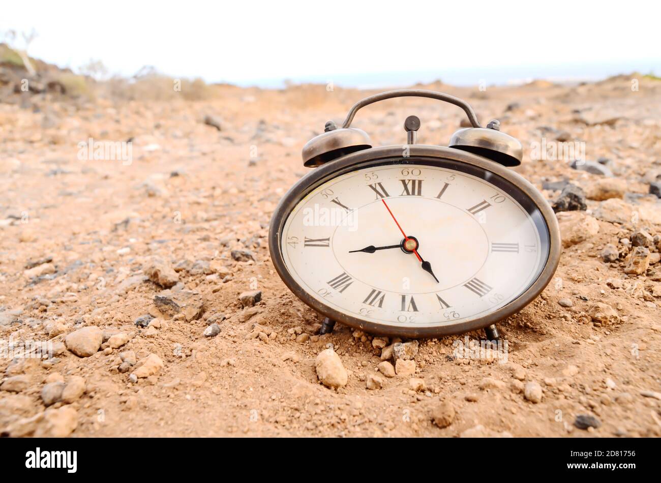 Classic Analog Clock In The Sand Stock Photo - Alamy