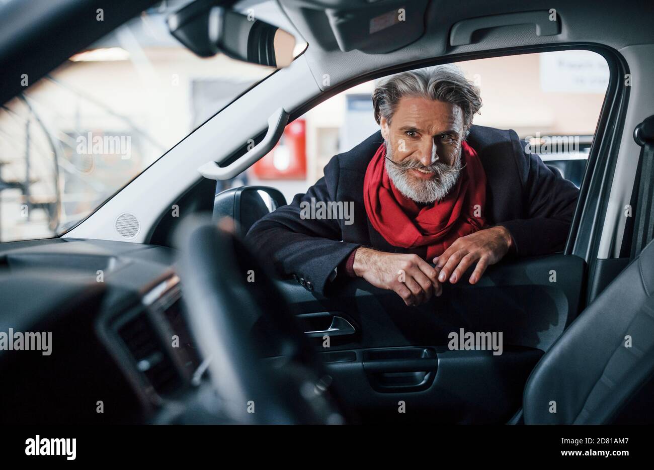 Fashionable old man with grey hair and mustache looking for a new car ...