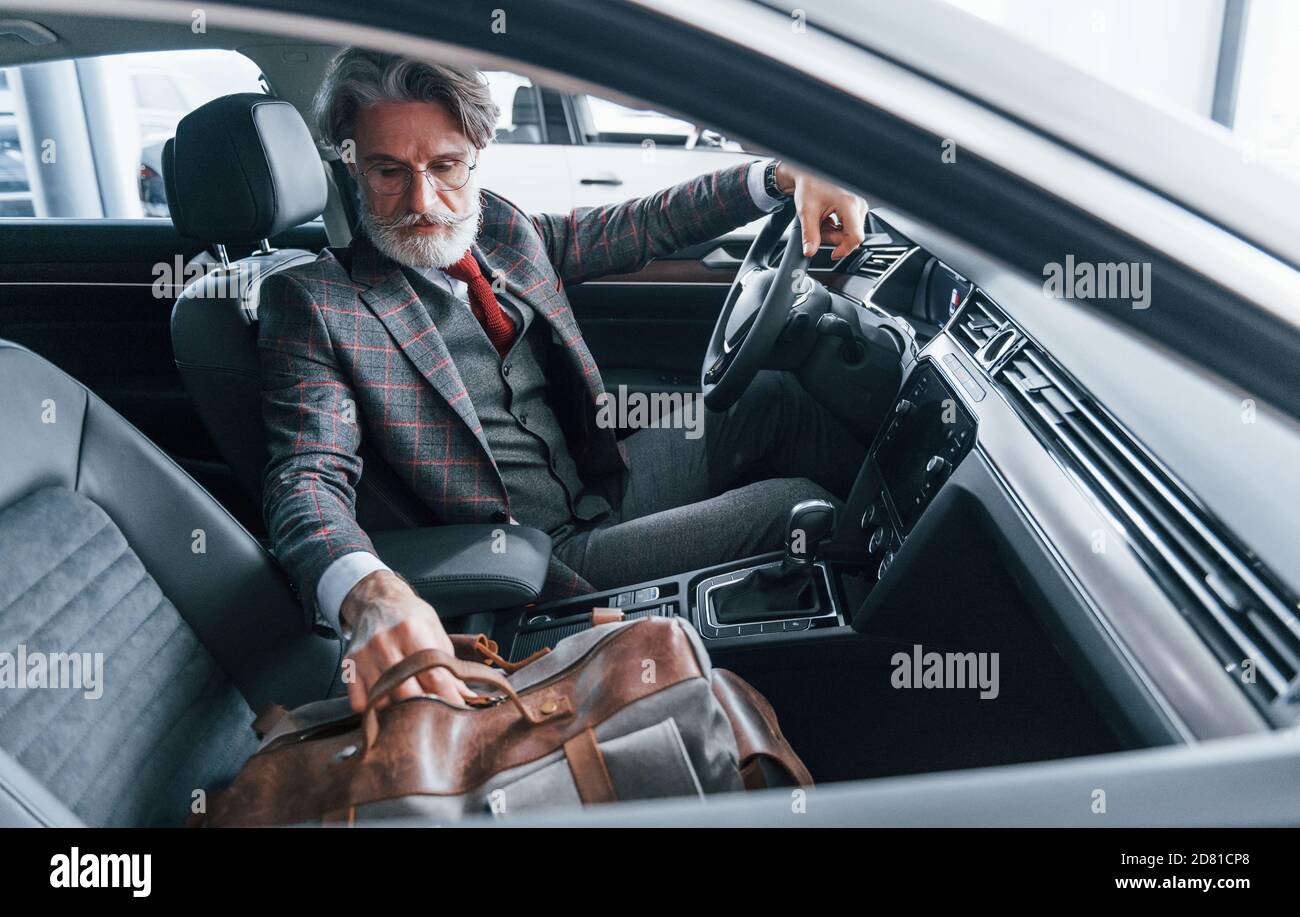 Fashionable senior man with grey hair and mustache on vacation with bag ...