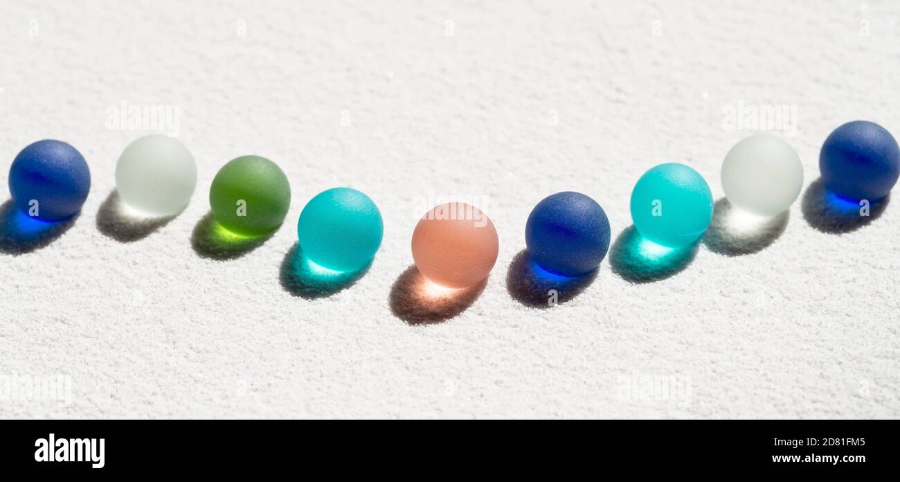 Colorful marbles on white sand background Stock Photo - Alamy