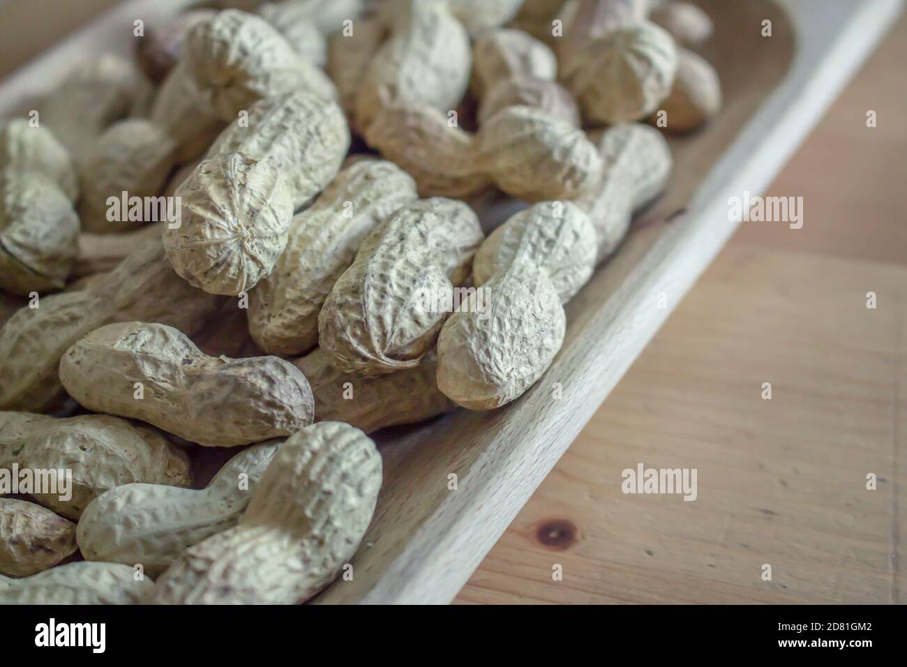 Some whole American peanuts with shell inside a rectangular wooden tray ...