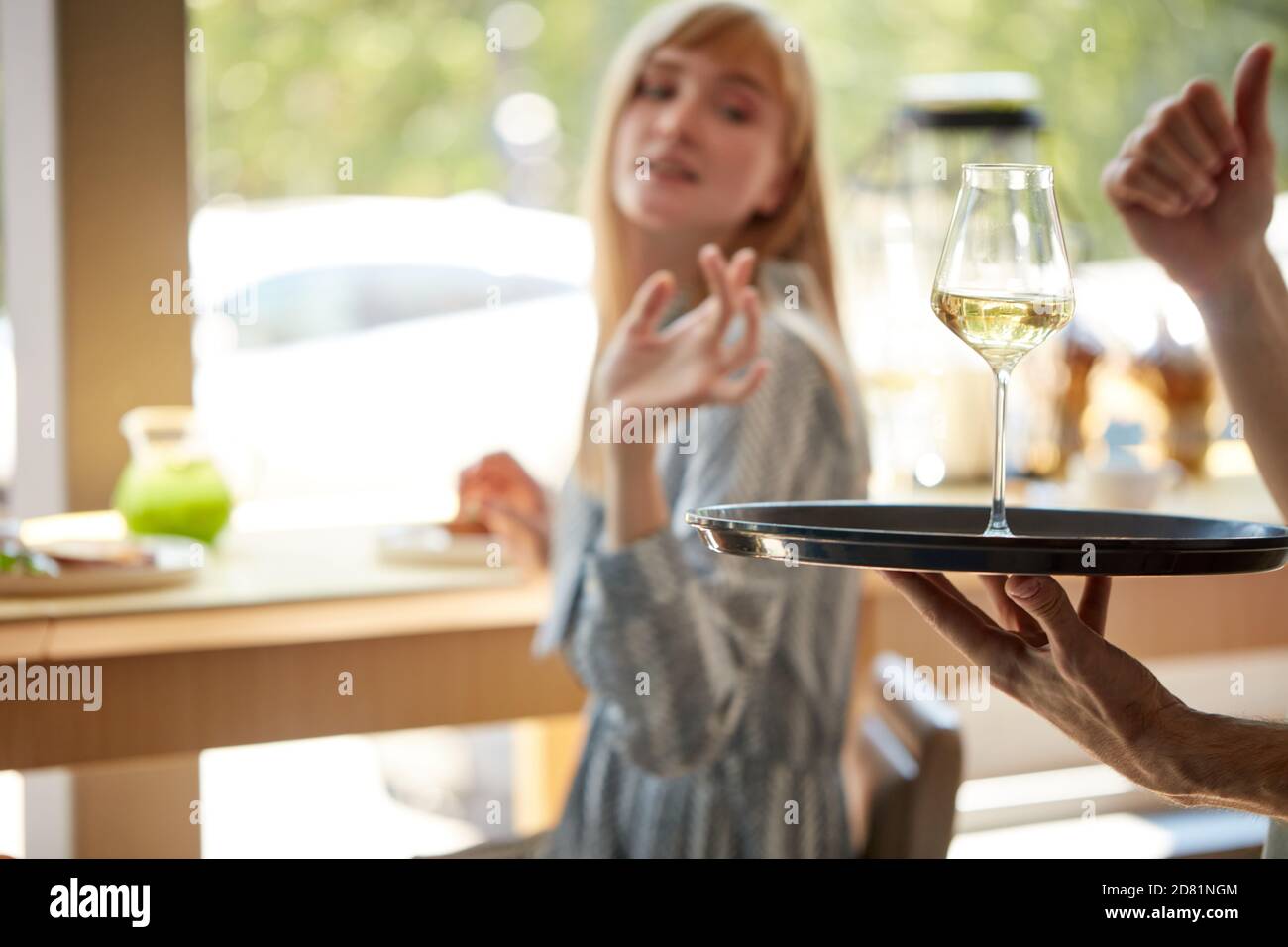 glad waiter bring glass of champagne on tray to customers, treats women ...