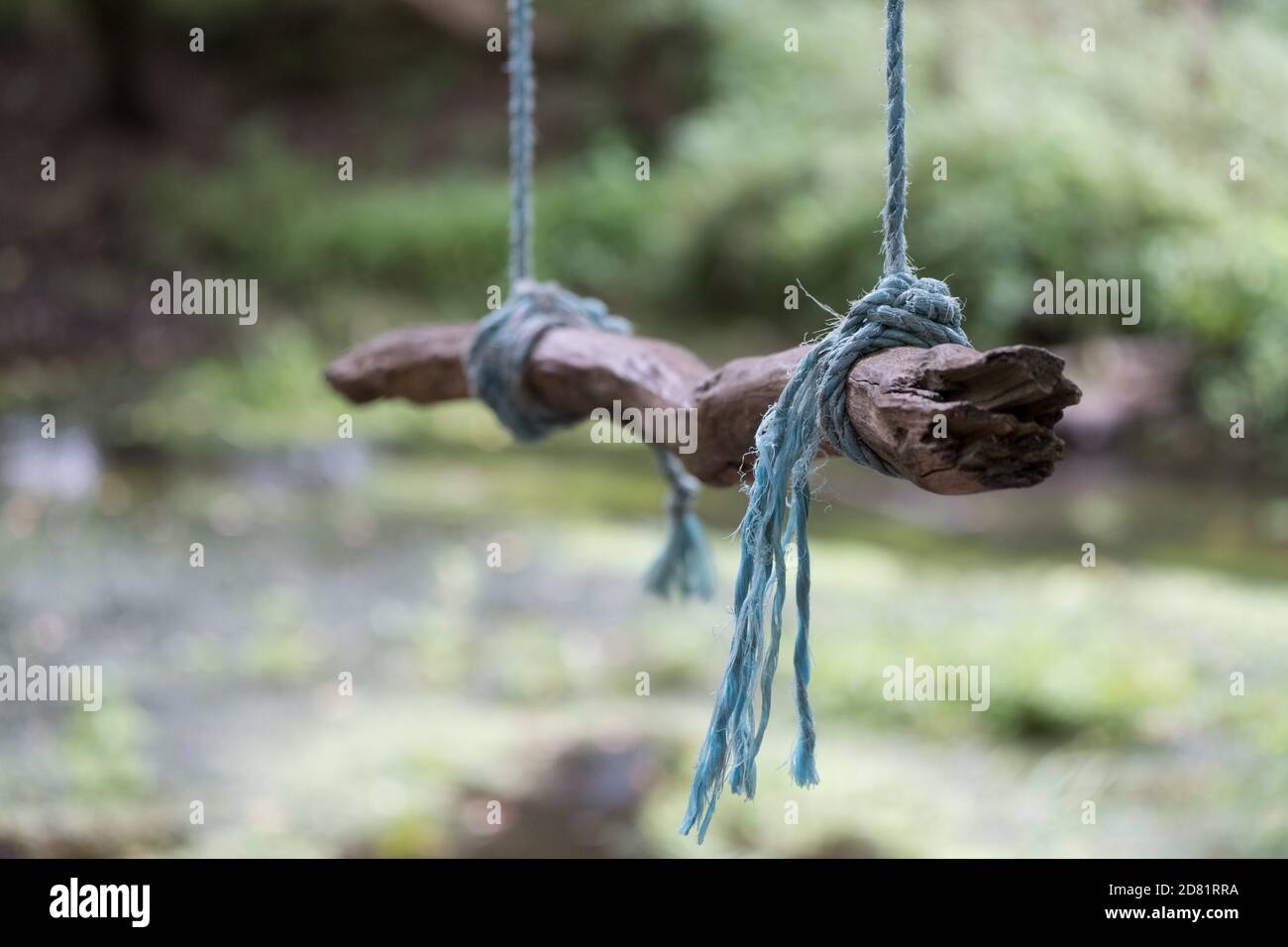Handmade rope and wooden swing hanging over a stream in nature in the ...