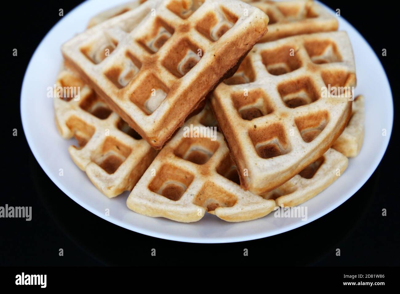 Belgian waffles in white plate on black glass table. Healthy breakfast ...