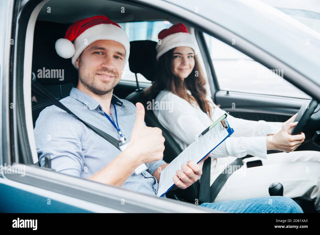 Young female driving student and male instructor in santa claus hats ...