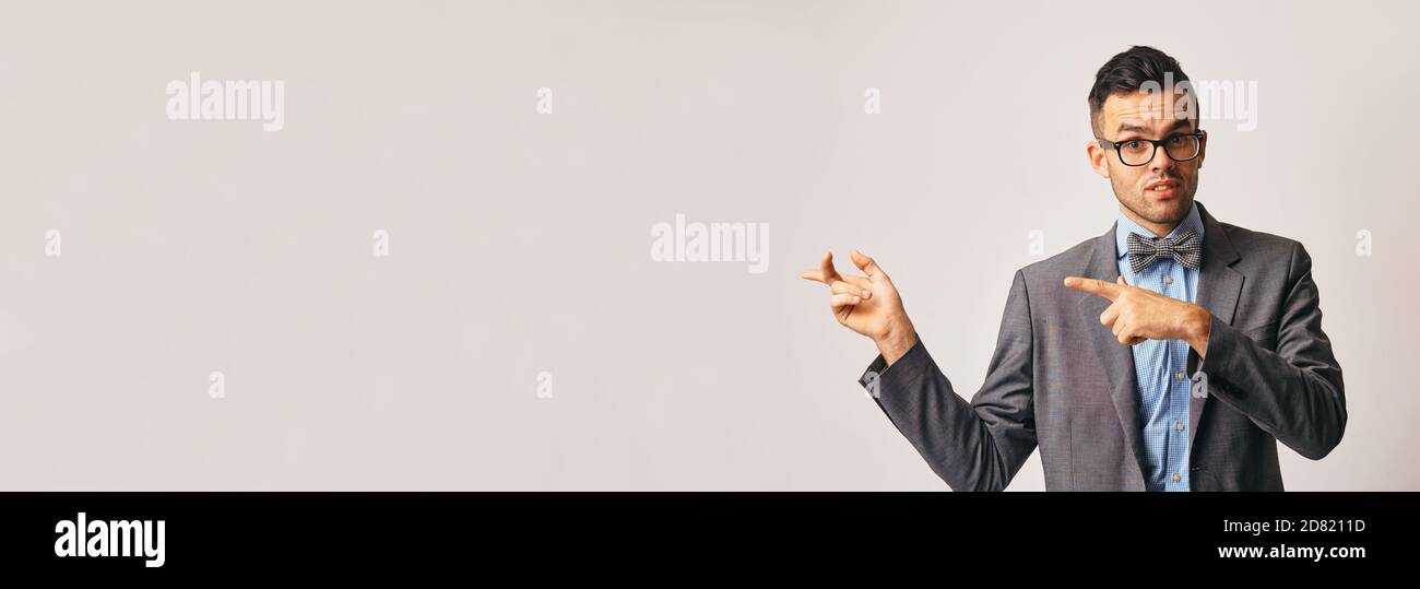Young man standing over white background, pointing to right, smiling ...