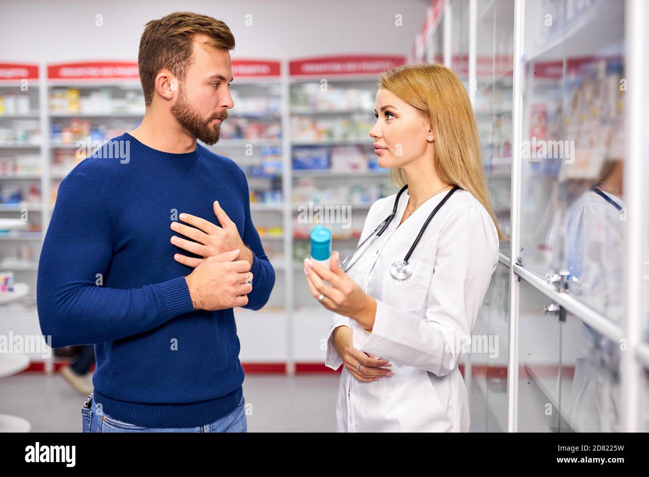 young caucasian helpful female druggist dealing with a male customer ...