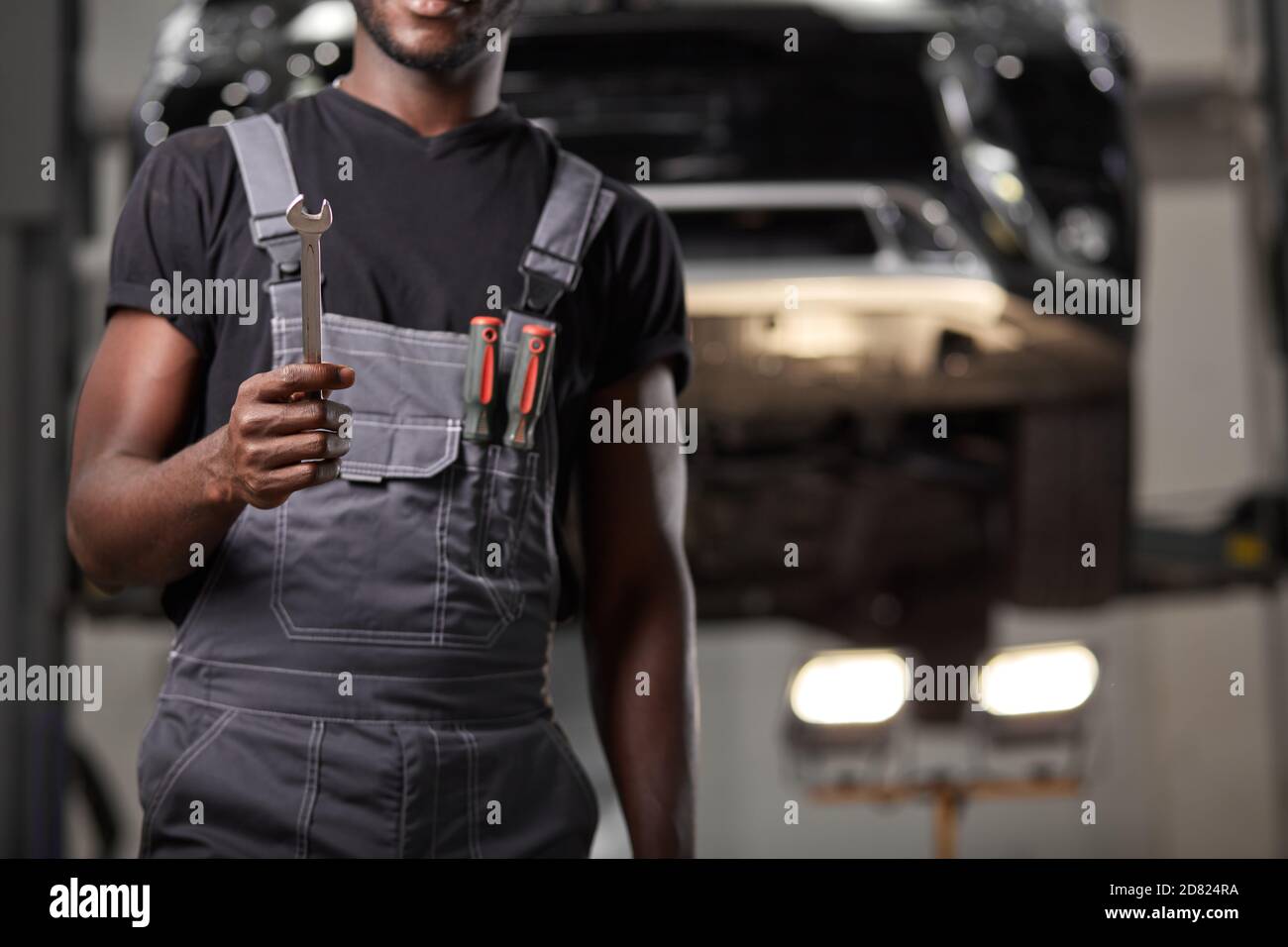cropped black afro auto mechnic holding tool for repairing a car ...