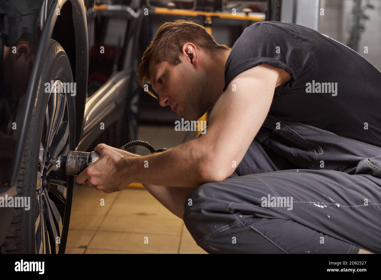 concentrated professional auto mechanic man repairs a wheel that has ...