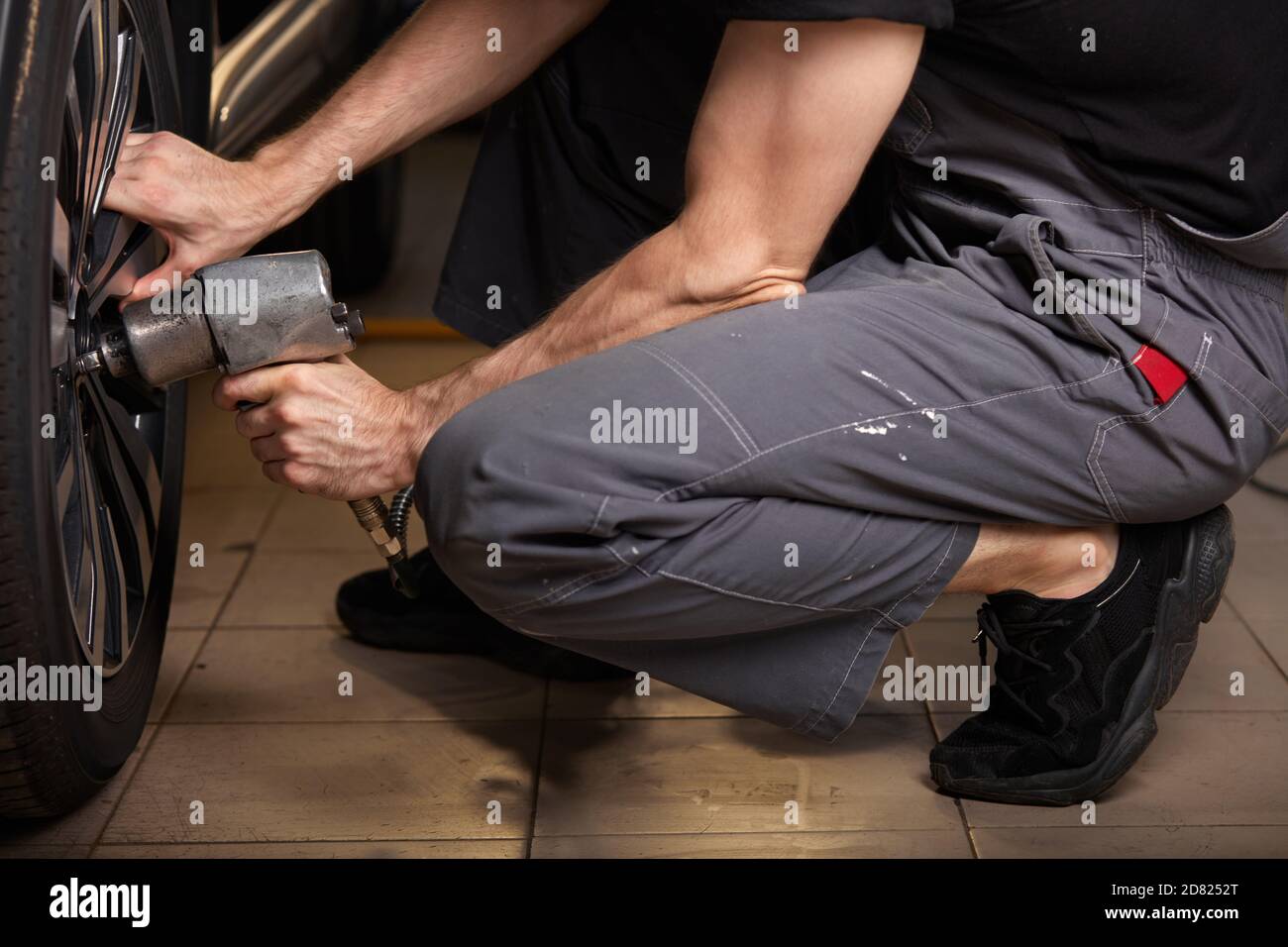 concentrated professional auto mechanic man repairs a wheel that has ...