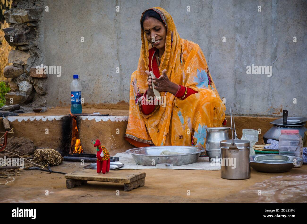 Woman making Woman making Chapati/Roti (breads) outside her house. She ...
