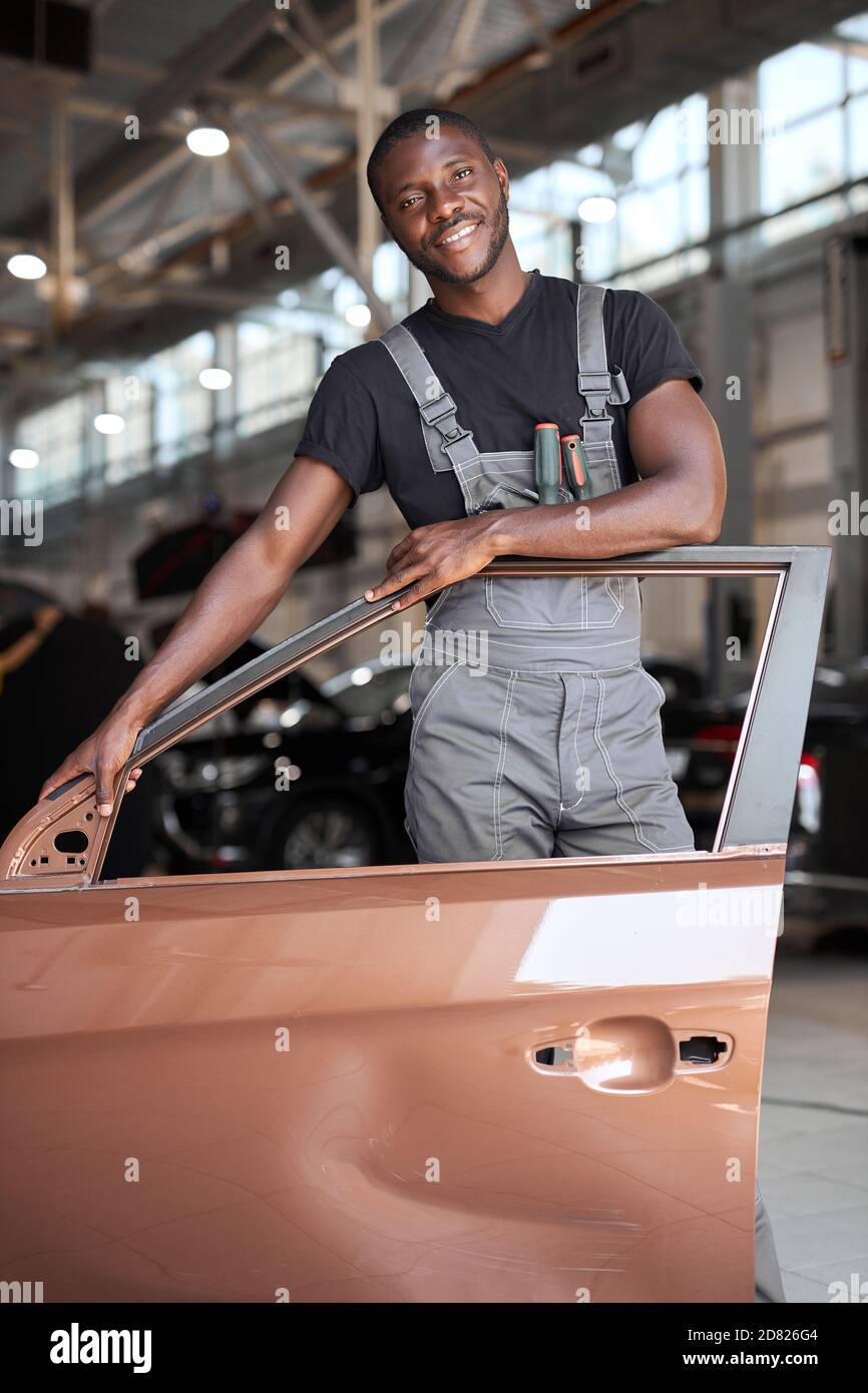 portrait of positive afro american auto mechanic in uniform posing ...