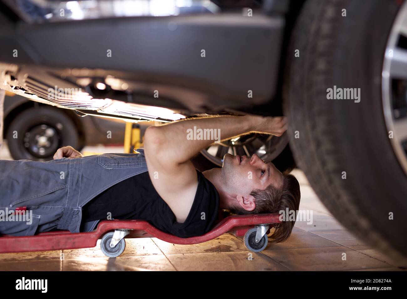 side view on concentrated auto mechanic male working alone on the floor ...