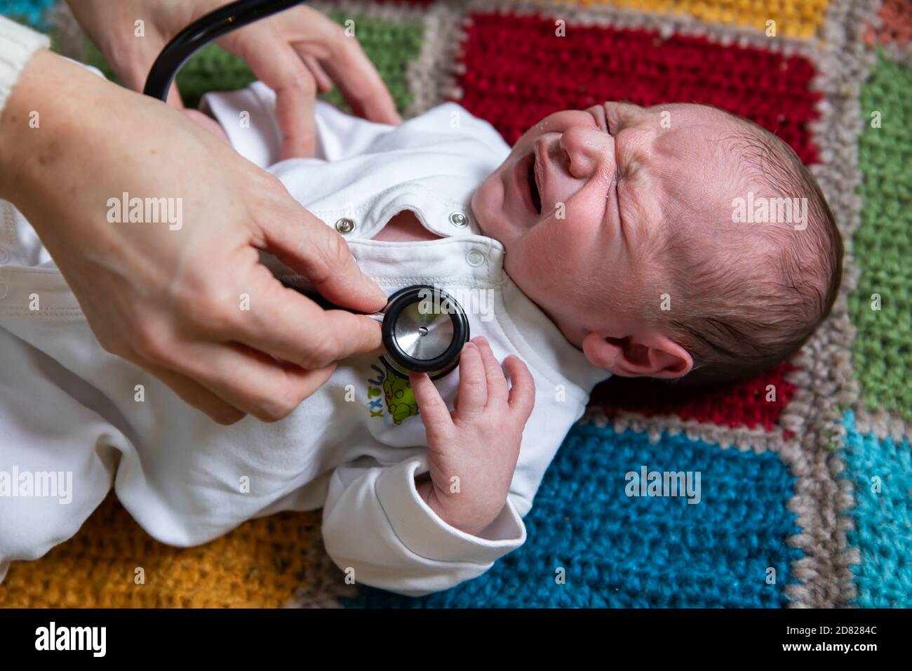 Portrait of newborn baby crying while suffering from illness and ...