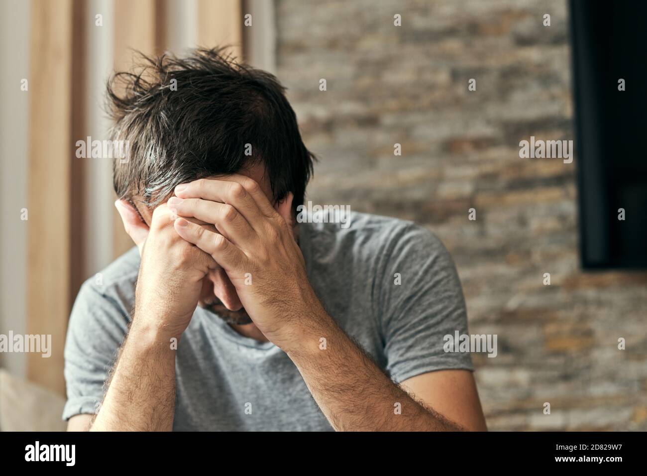 Depressed sulking man sitting alone at living room sofa and thinking ...