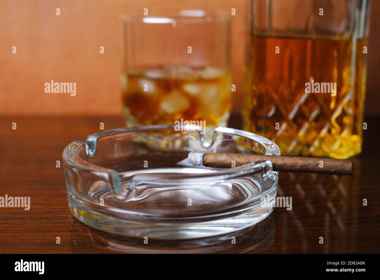 Lighted cigar in a glass round ashtray close-up, selective focus, bokeh ...