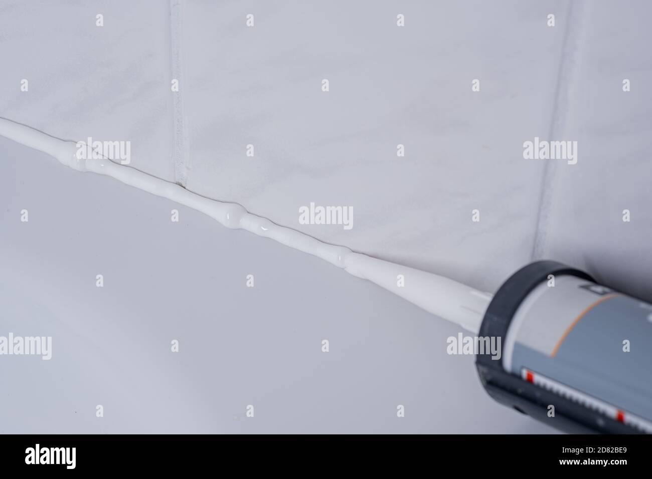 Plumber Applying silicone sealant to the tile joint Stock Photo - Alamy