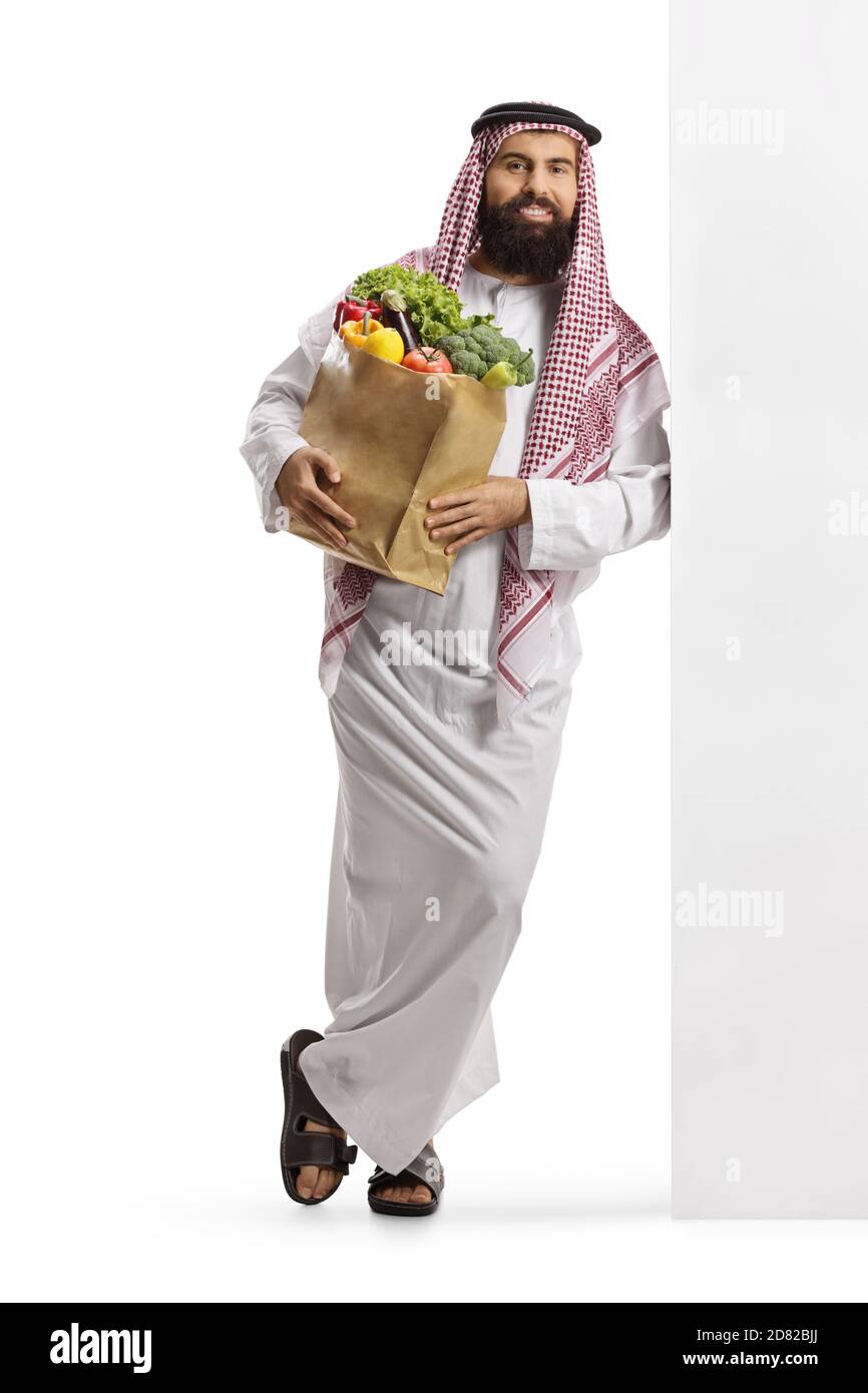 Arab man with a grocery bag standing and leaning on a wall isolated on ...