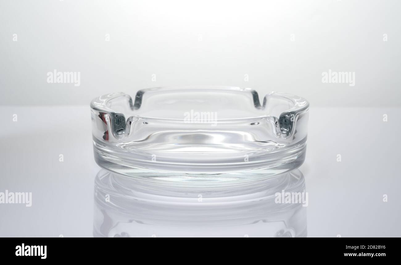Transparent glass ashtray on a glossy light background Stock Photo - Alamy