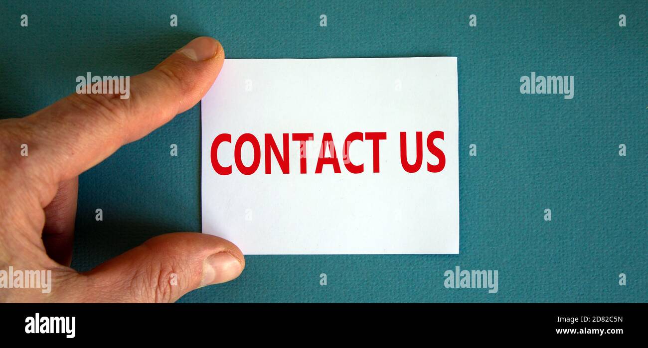 Word 'contact us' on the white card between fingers. Beautiful blue ...