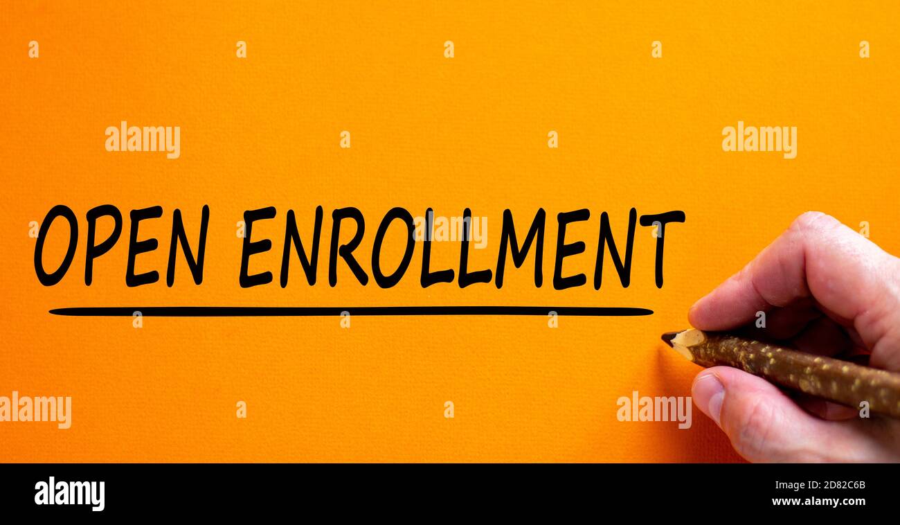 Hand writing 'open enrollment', isolated on beautiful orange background ...