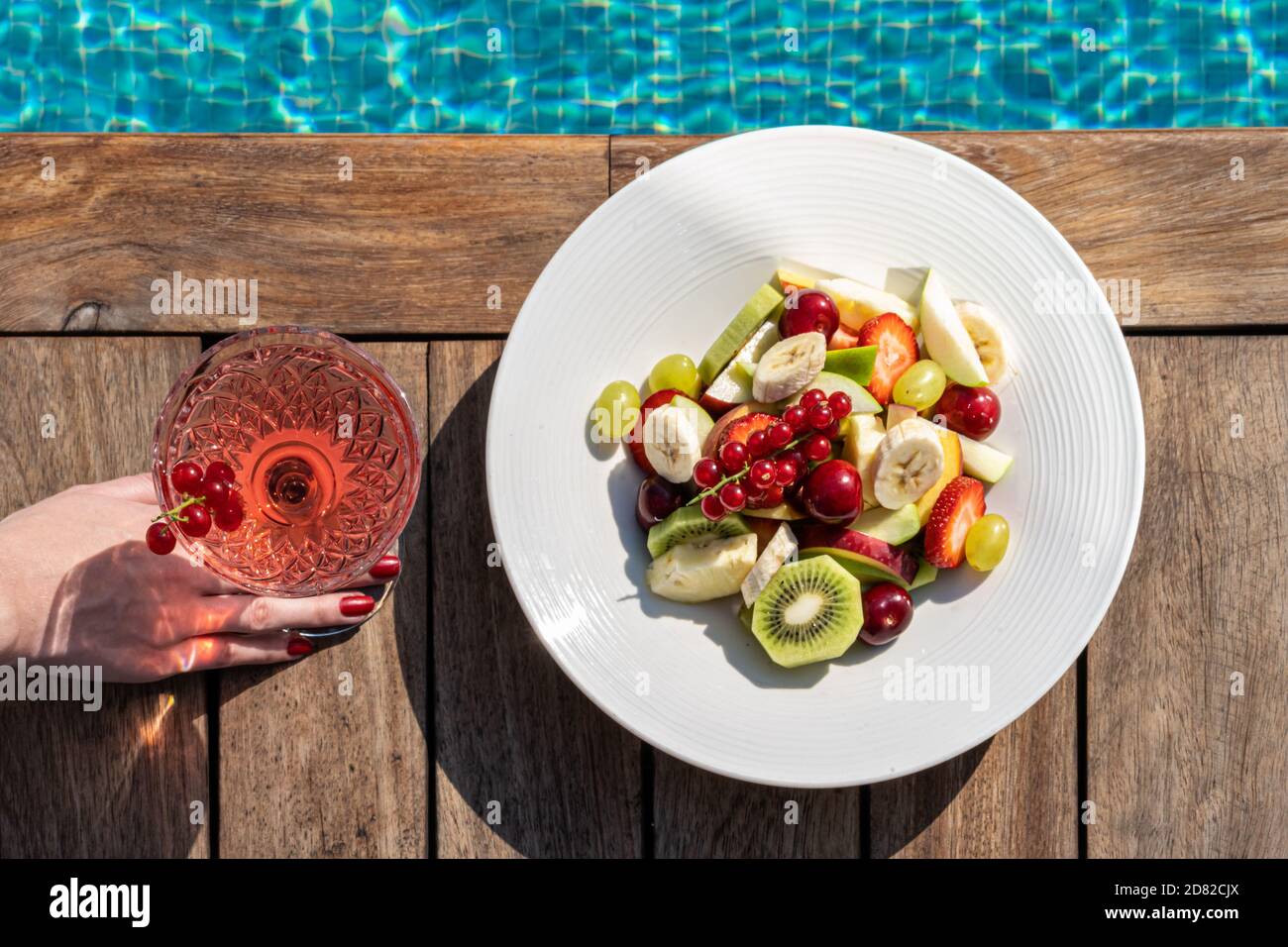 refreshing cocktail and fruits and berries plate near swimming pool in ...