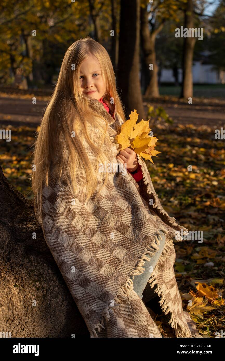 little blonde girl in a plaid whip in the park in autumn Stock Photo ...