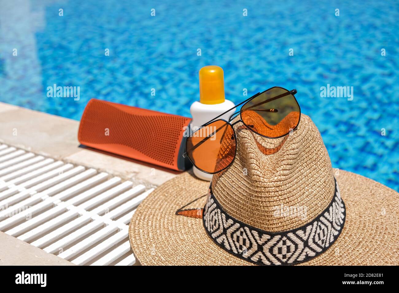 orange coloured beach accessories near swimming pool. Sun cream ...