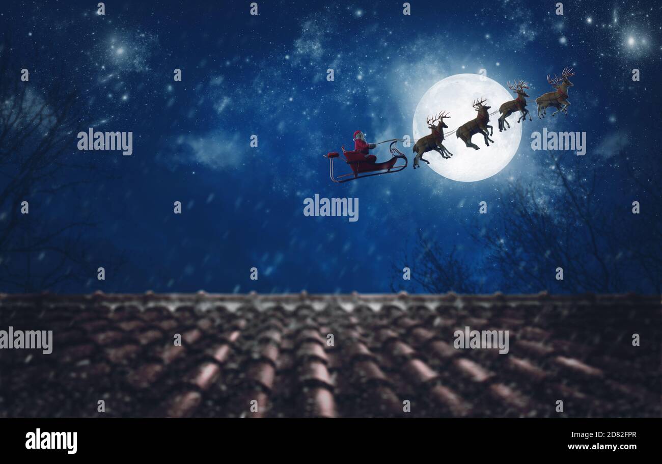 Santa Claus on his sleigh, pulled by reindeer, flying at night to ...