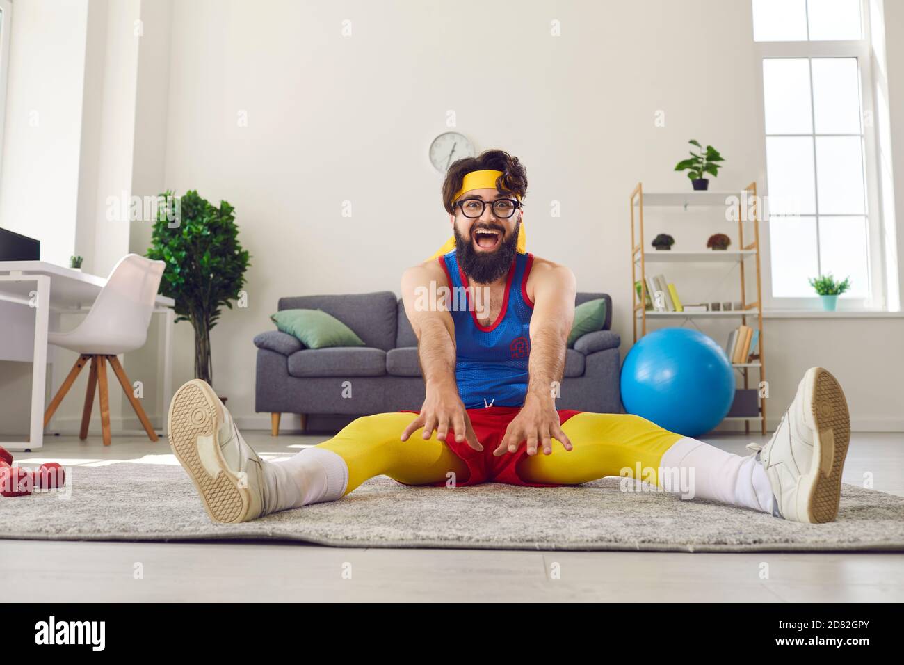 Funny young man trying to become more fexible and doing seated forward ...